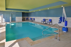Piscina com deck ladrilhado, cadeira de salva-vidas e vestiário.