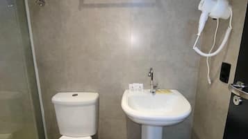 Uma casa de banho moderna com sanita, bidé, lavatório e um secador de cabelo fixado na parede.