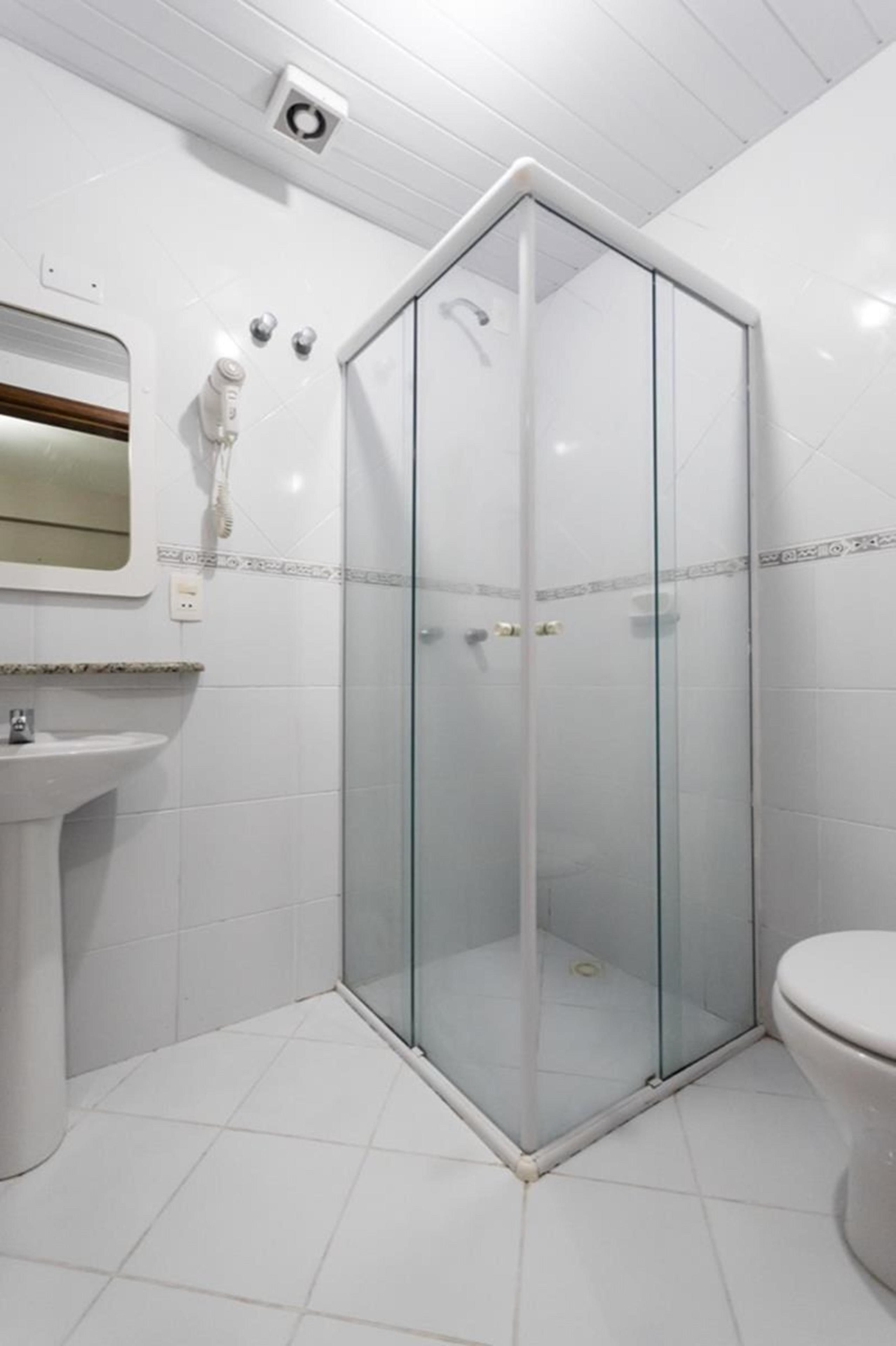 Uma casa de banho moderna com chuveiro em cabine de vidro, lavatório e sanita.
