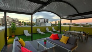 Terraço no telhado com sofá, cadeiras, mesa e planta em vaso.