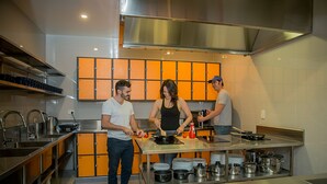 Uma cozinha moderna com eletrodomésticos de aço inoxidável, armários de armazenamento laranja e uma ilha central com utensílios de cozinha.