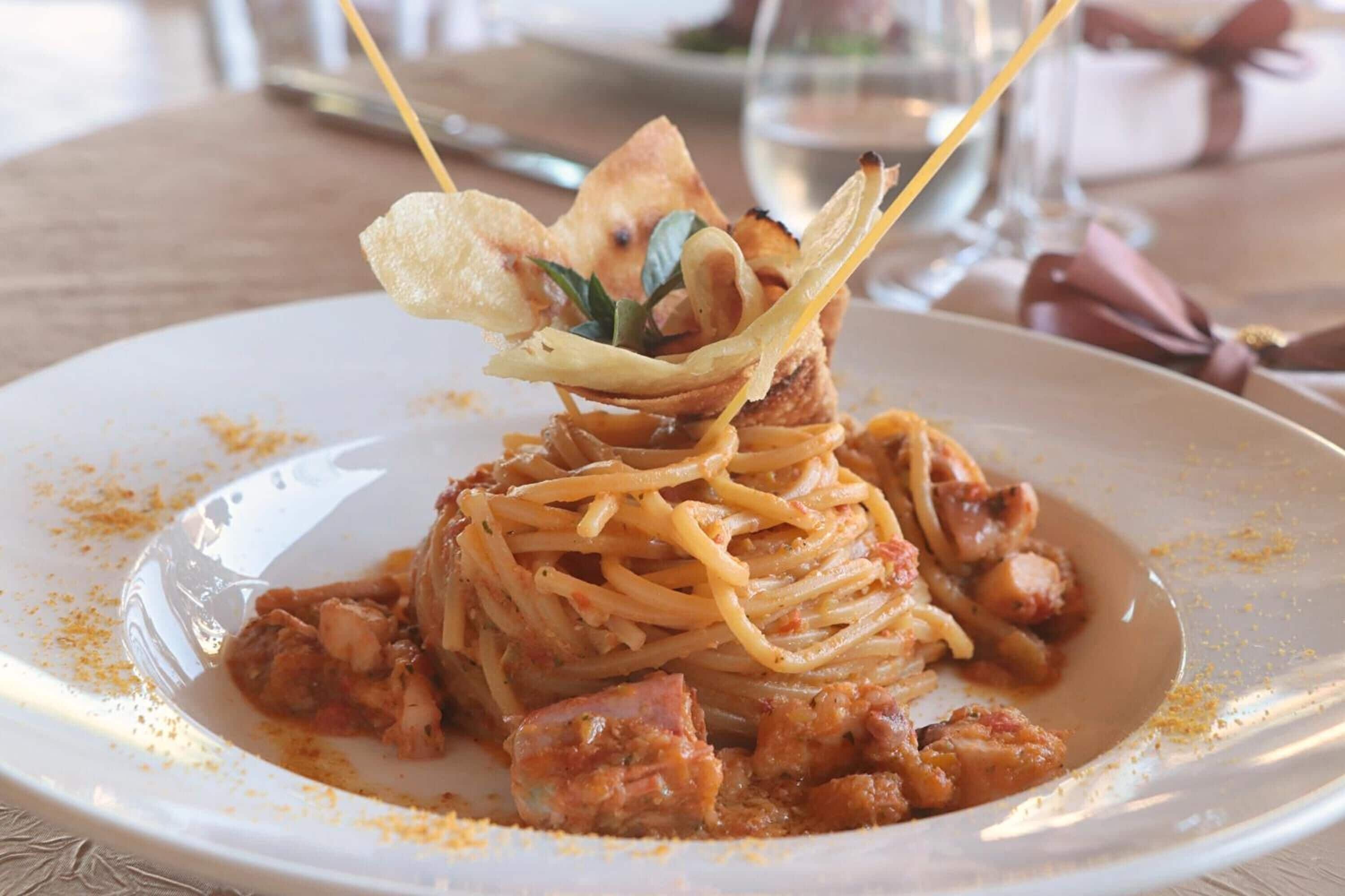 Um prato de espaguete com molho à base de carne e guarnição de elementos crocantes.