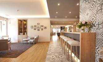 Um hall de hotel moderno com área de bar, assentos e piso estampado.