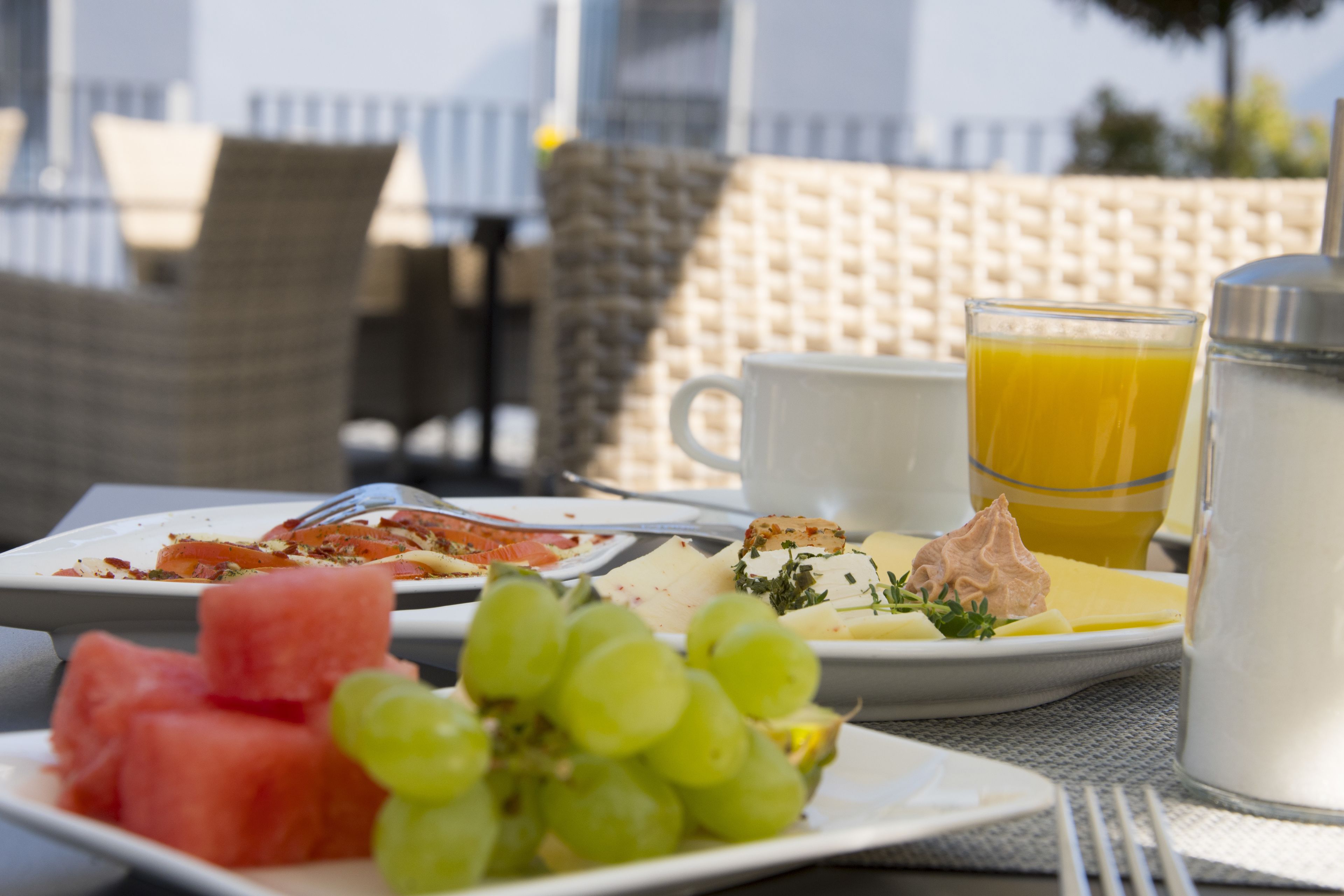 Uma mesa de café da manhã com pratos de comida, um copo de suco de laranja e um jarro de leite.