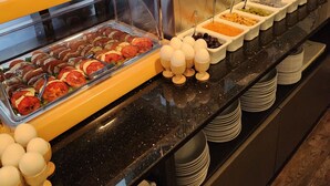 Buffet com diversas opções de comida, incluindo carnes, queijos e frutas.