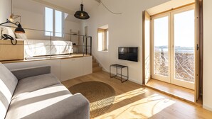 Uma sala de estar moderna com sofá, televisão, escada e janelas amplas.