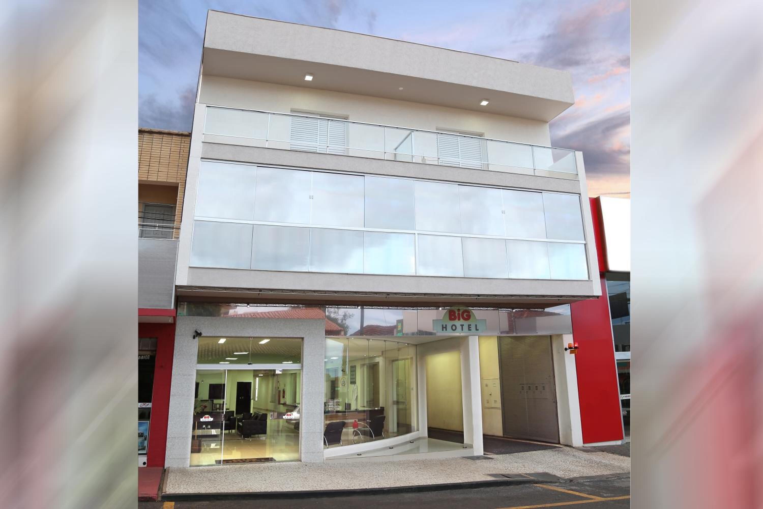 Um edifício de dois andares com fachada de vidro e uma placa com a inscrição 'BIG HOTEL'.