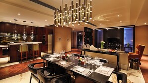 Área de refeições de um hotel moderno, com uma mesa comprida posta para uma refeição, um bar e um espaço de estar com vista.