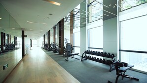 Uma academia com equipamentos de ginástica, grandes janelas e piso de madeira.