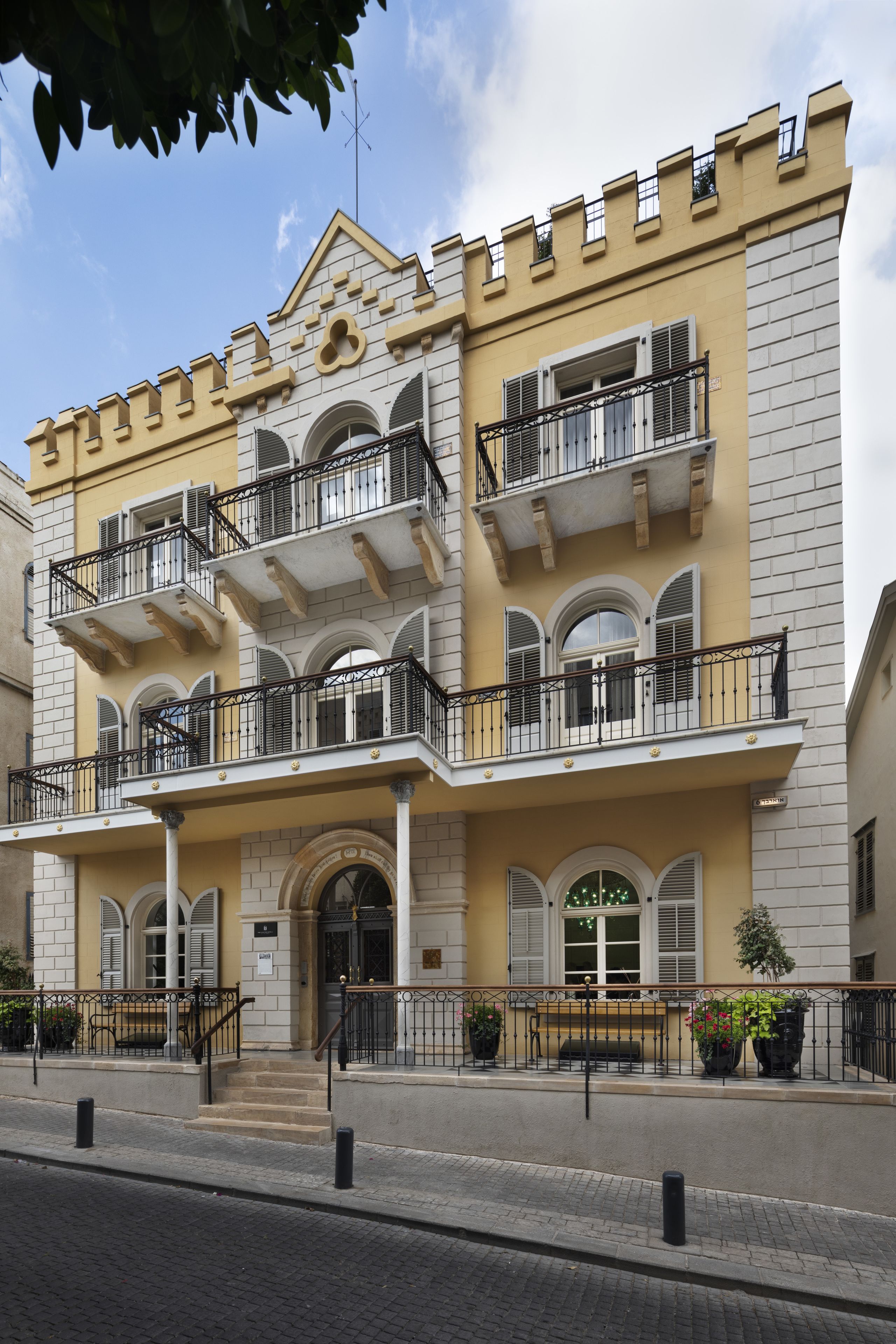 Um edifício de vários andares com varandas, uma entrada central e fachada de tijolos.