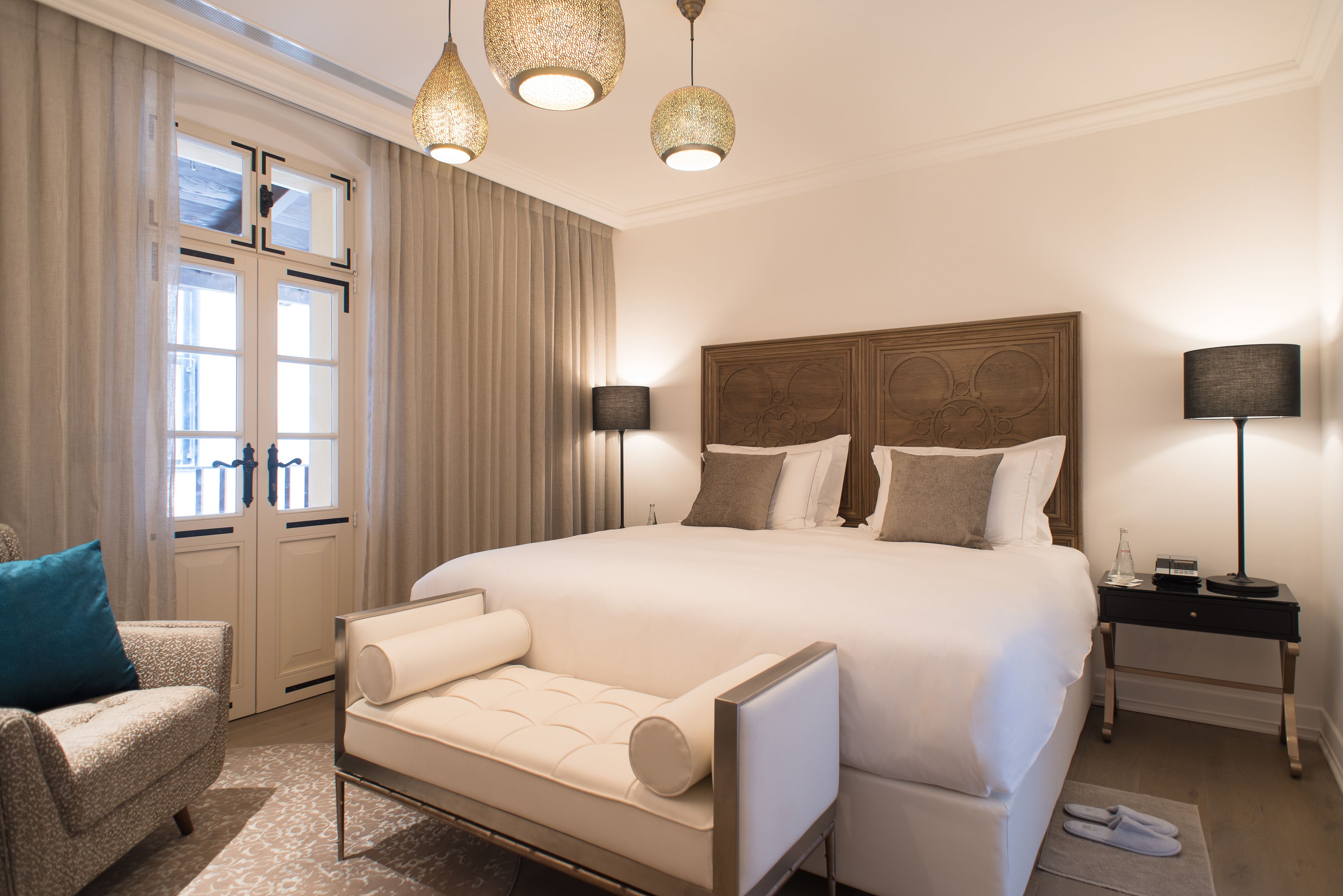 Um quarto espaçoso com uma cama grande, um espaço de estar com um sofá e uma mesa de cabeceira com abajur.