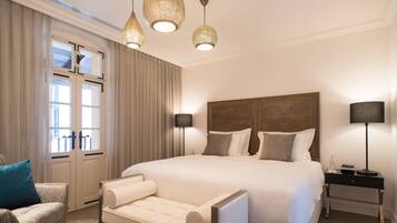 Um quarto espaçoso com uma cama grande, um espaço de estar com um sofá e uma mesa de cabeceira com abajur.