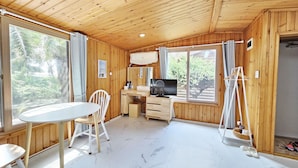 Quarto com painéis de madeira, uma mesa, uma cadeira e uma televisão.