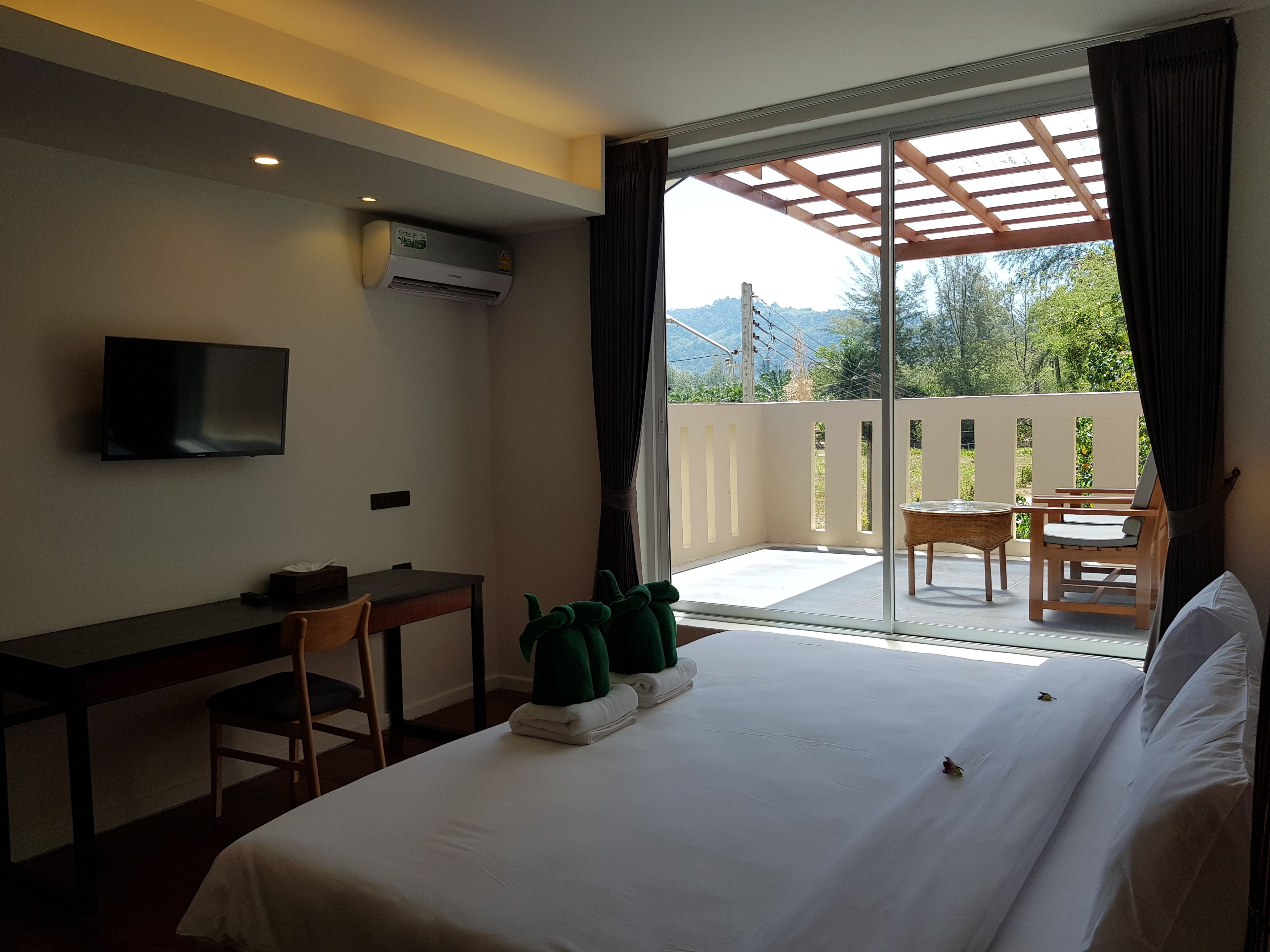 Quarto de hotel com cama, escrivaninha, cadeira, televisão, ar condicionado e varanda com vista para o exterior.