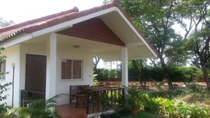 Uma casa pequena com varanda, mesa de jantar e cadeiras.