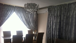 Um quarto com uma mesa de jantar e cadeiras, um sofá e um candelabro.