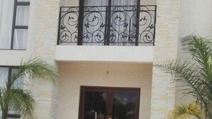 Um edifício de dois andares com varanda e grades de ferro ornamentadas.