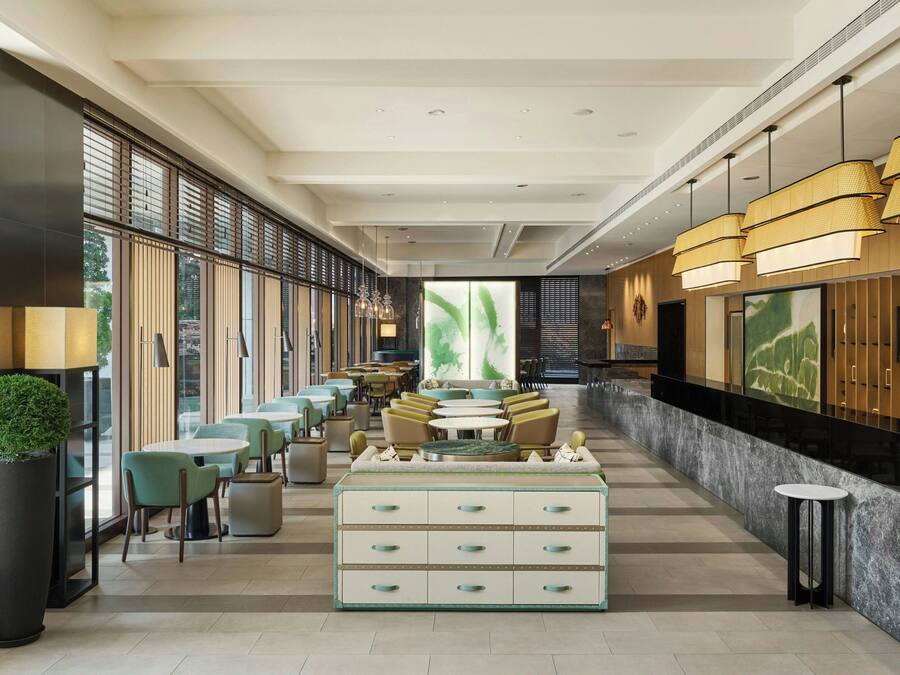 Um hall de hotel moderno com um balcão de recepção extenso, área de estar e grandes janelas.