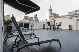 Terraço no telhado com vista para o horizonte da cidade, incluindo um edifício alto em construção.