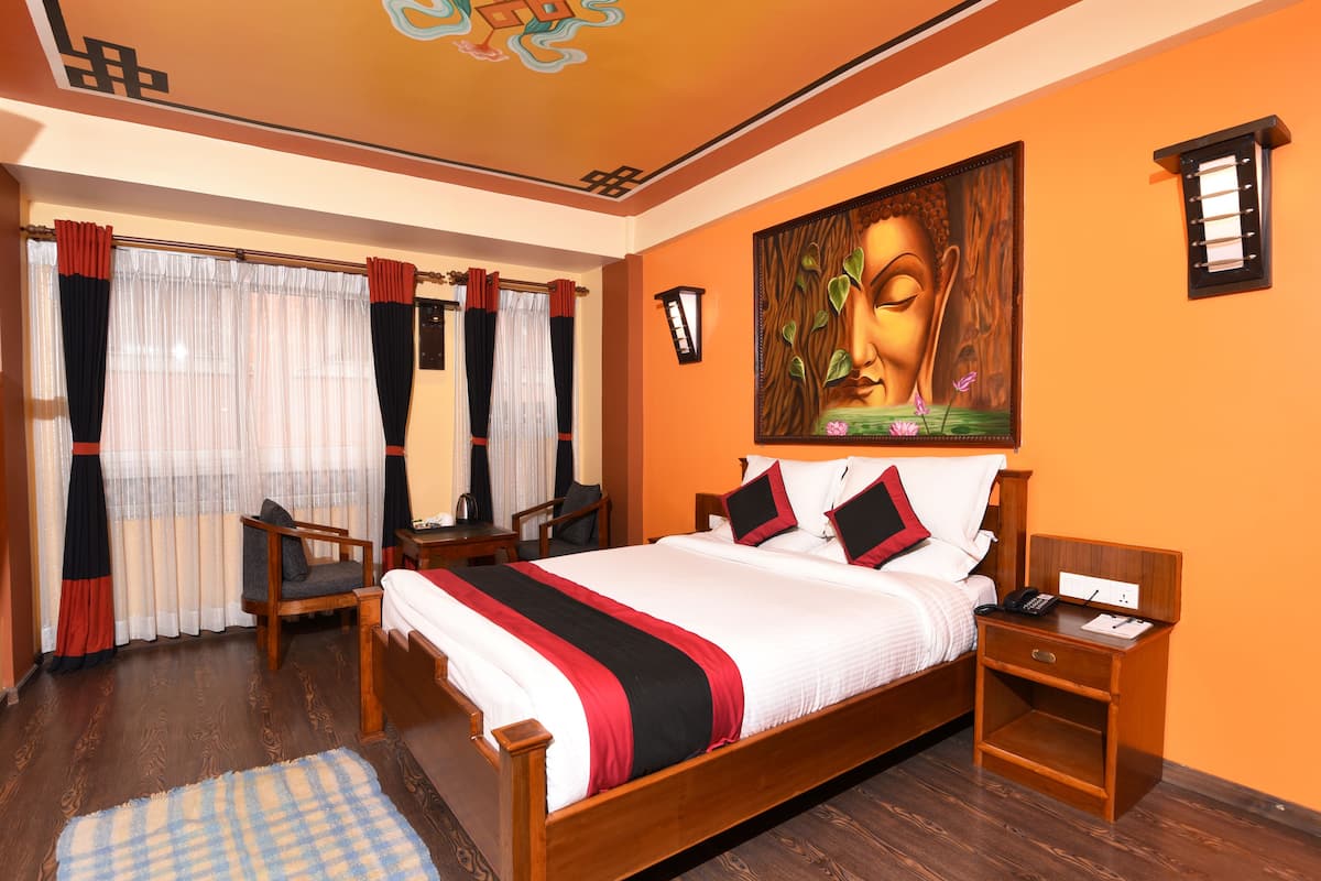 Quarto de hotel com cama de madeira, mesa de cabeceira, escrivaninha e cadeira.