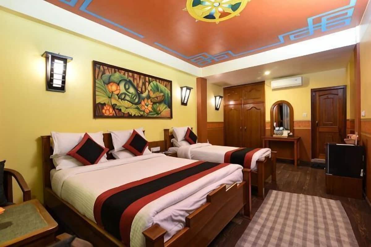 Quarto de hotel com duas camas, uma escrivaninha, uma cadeira, um espelho e uma porta.
