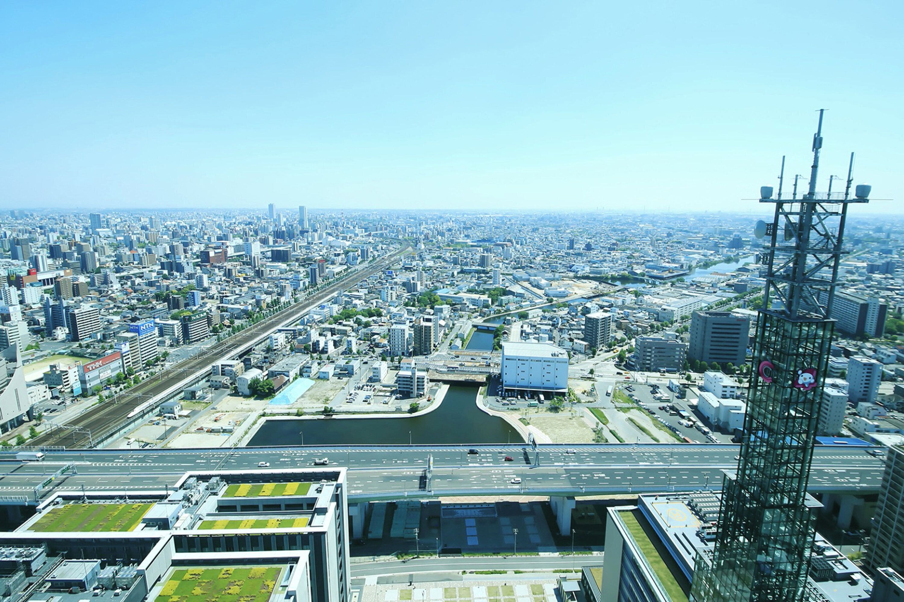 Paisagem urbana com um rio, edifícios altos e uma torre de comunicação imponente.