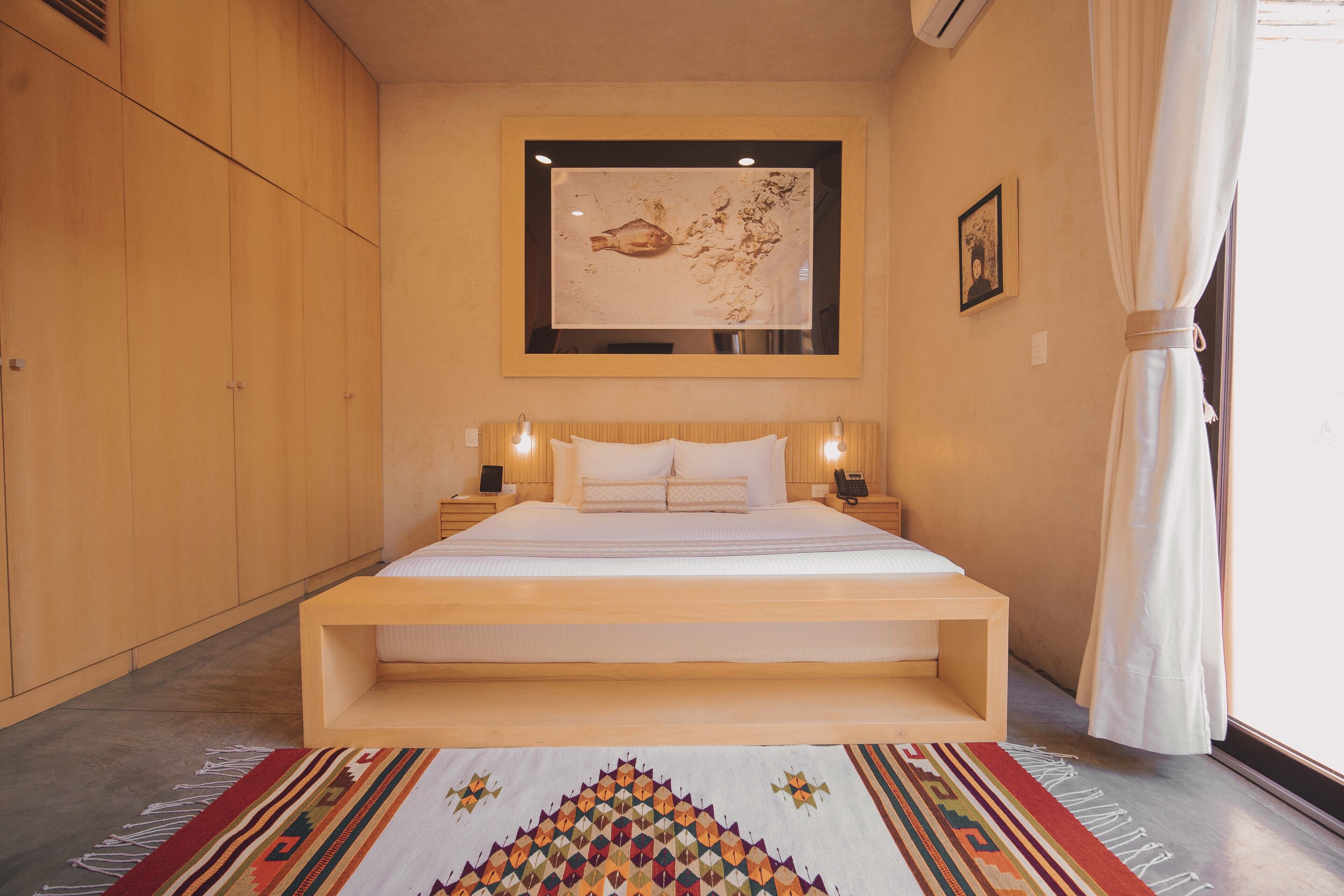 Quarto com cama grande, guarda-roupa de madeira e uma obra de arte emoldurada na parede.