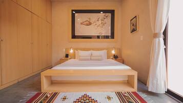 Quarto com cama grande, guarda-roupa de madeira e uma obra de arte emoldurada na parede.