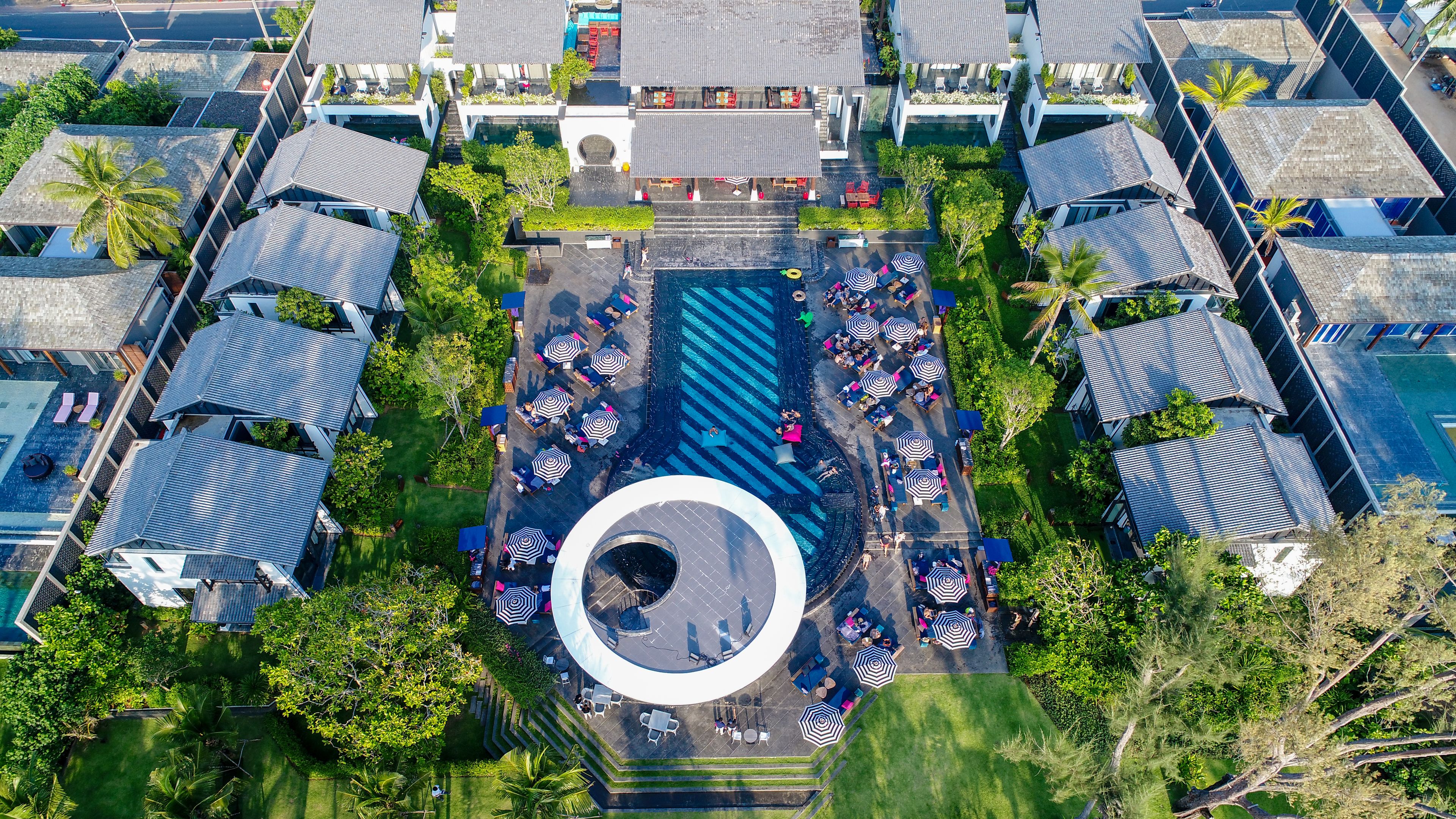Vista aérea de um resort com vários edifícios, uma piscina central e áreas de estar ao ar livre.