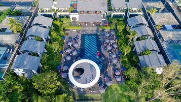 Vista aérea de um resort com vários edifícios, uma piscina central e áreas de estar ao ar livre.