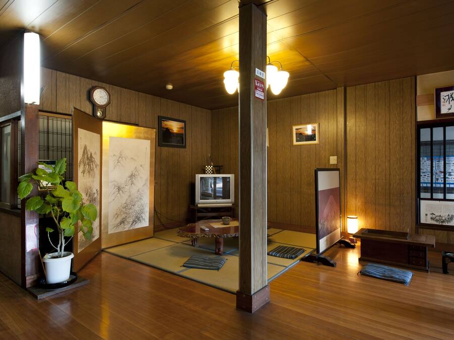 Um quarto japonês tradicional com tatames, uma televisão, um relógio e diversas obras de arte.