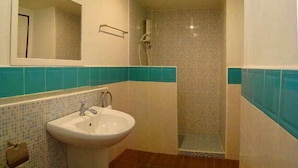 Casa de banho com lavatório, espelho e chuveiro.