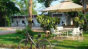 Uma bicicleta estacionada perto de um edifício branco com área de estar coberta e plantas em vasos.