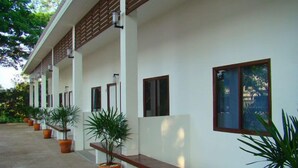 Um edifício com galeria coberta, plantas em vasos e um banco.