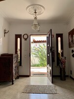 Um corredor com um armário de madeira, um candelabro e uma porta que dá para o exterior.