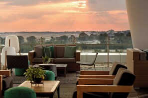 Uma área de estar moderna ao ar livre, com sofá, cadeiras e uma mesa, com vista para uma paisagem deslumbrante.