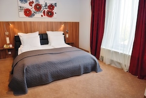 Uma cama com colcha cinza, almofadas brancas e cabeceira de madeira.