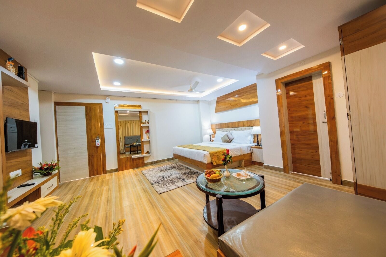 Quarto de hotel moderno com uma cama, mesa de cabeceira e um espaço de estar com uma mesa de vidro.