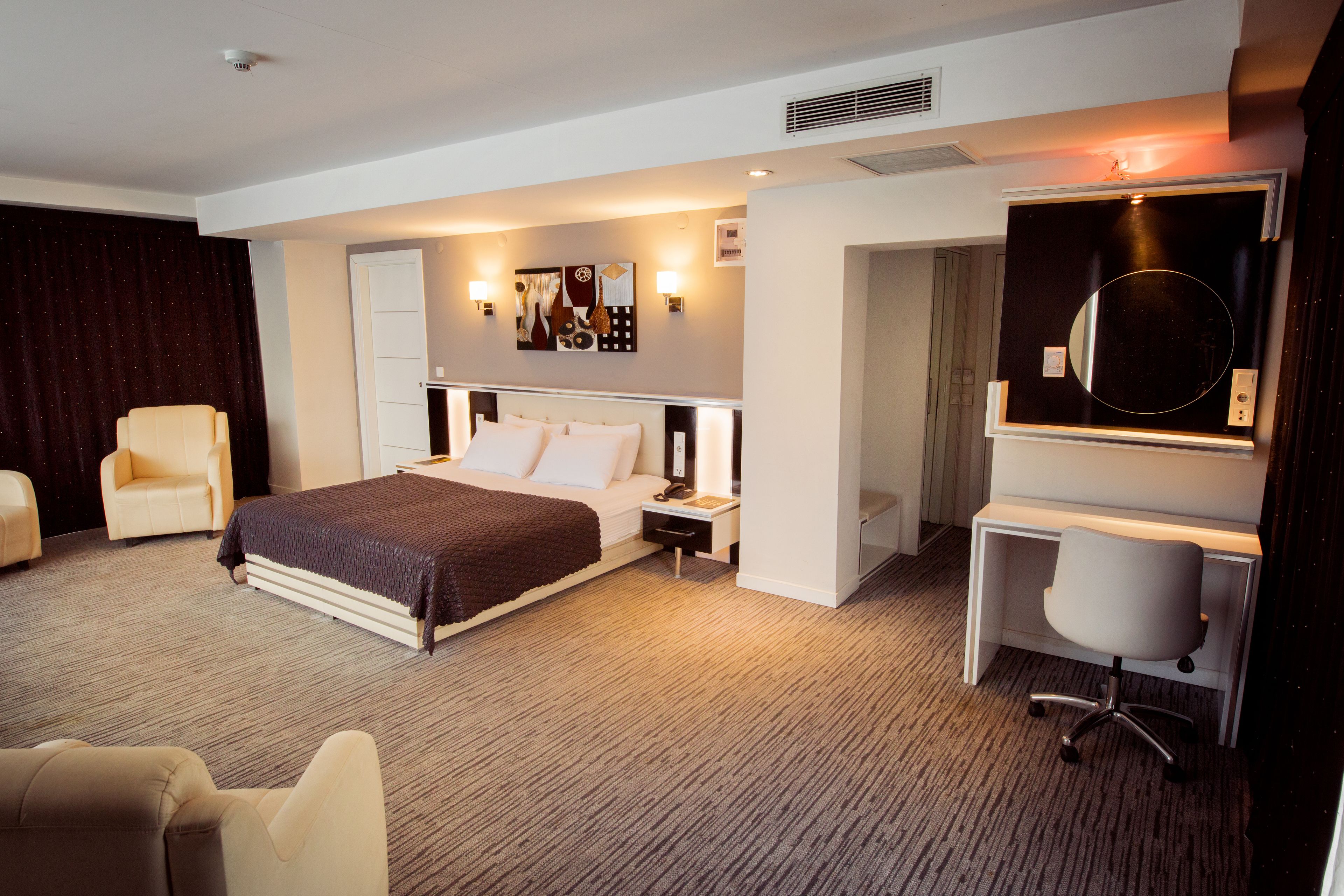 Quarto de hotel com uma cama grande, uma mesa, uma cadeira e um espelho.