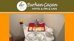 Uma bandeja com café, chá e lanches, um vaso com flores e uma caixa vermelha de cereais.