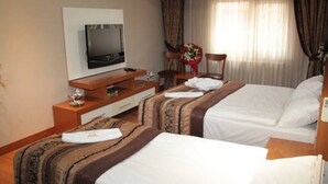Quarto de hotel com duas camas, uma televisão sobre suporte de madeira, uma escrivaninha e uma cadeira.