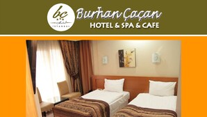 Quarto de hotel com duas camas, uma cadeira e um quadro na parede.