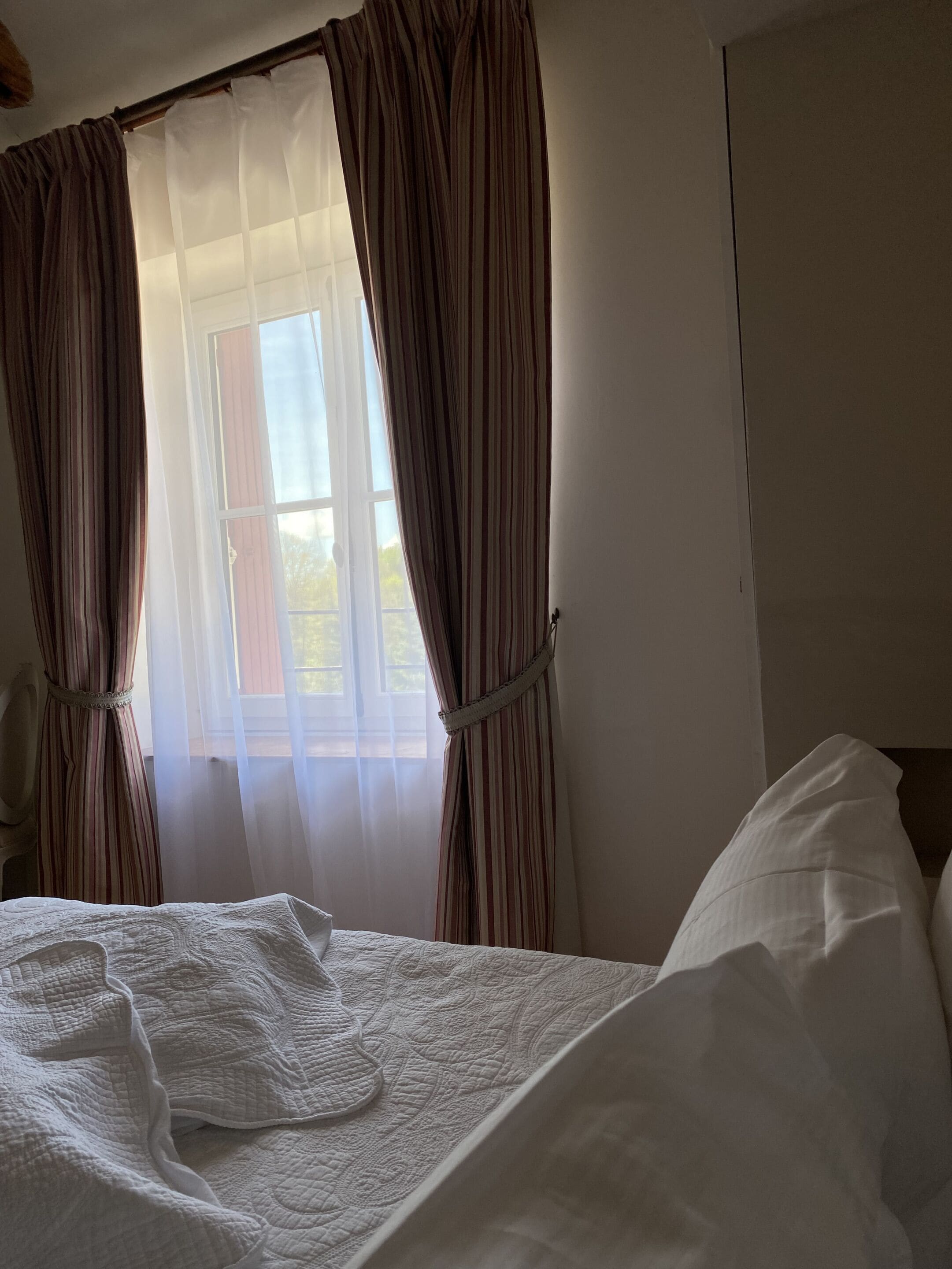 Quarto com cama, cortinas e janela.