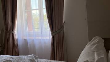 Quarto com cama, cortinas e janela.