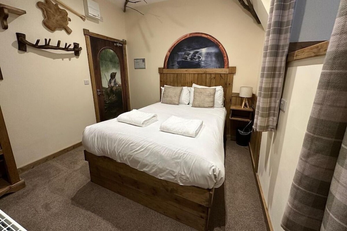 Um quarto com uma cama de madeira, uma cabeceira com arco circular e um porta-roupas fixado na parede.