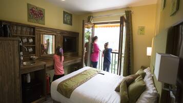 Quarto de hotel com cama, escrivaninha, janela e porta que dá para uma varanda.