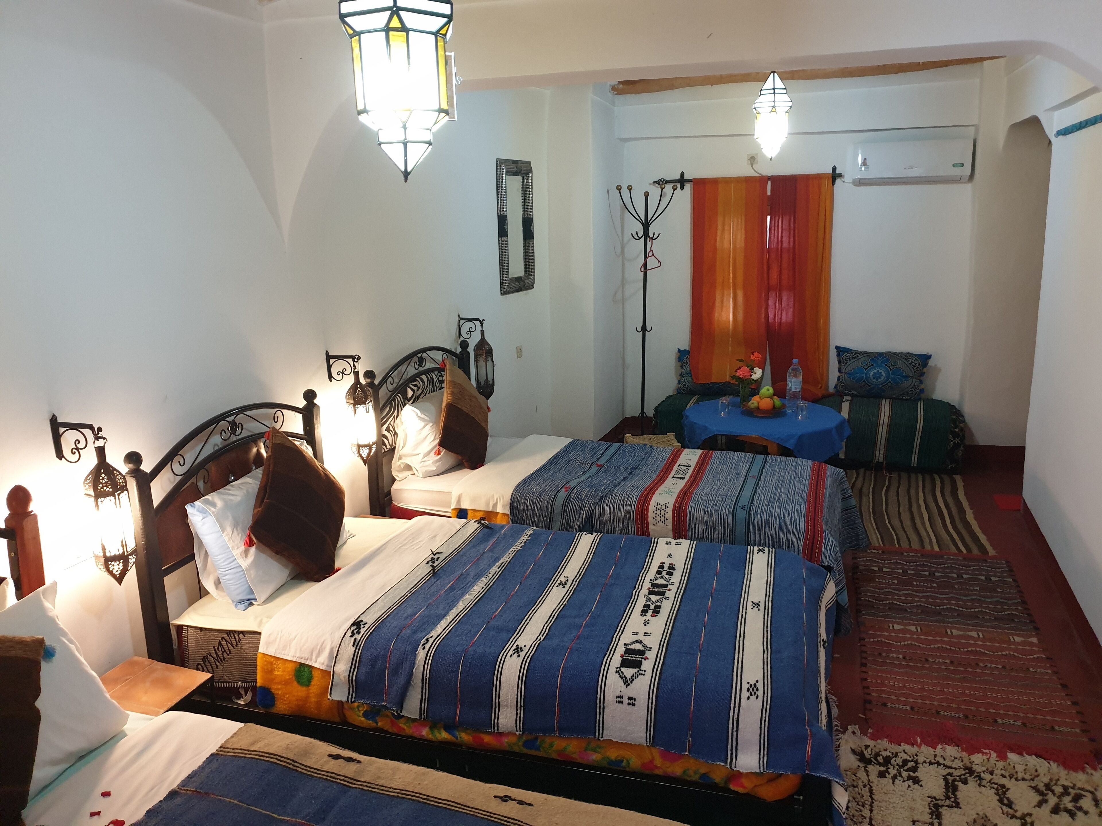 Quarto com duas camas, uma mesa com uma fruteira e um abajur.