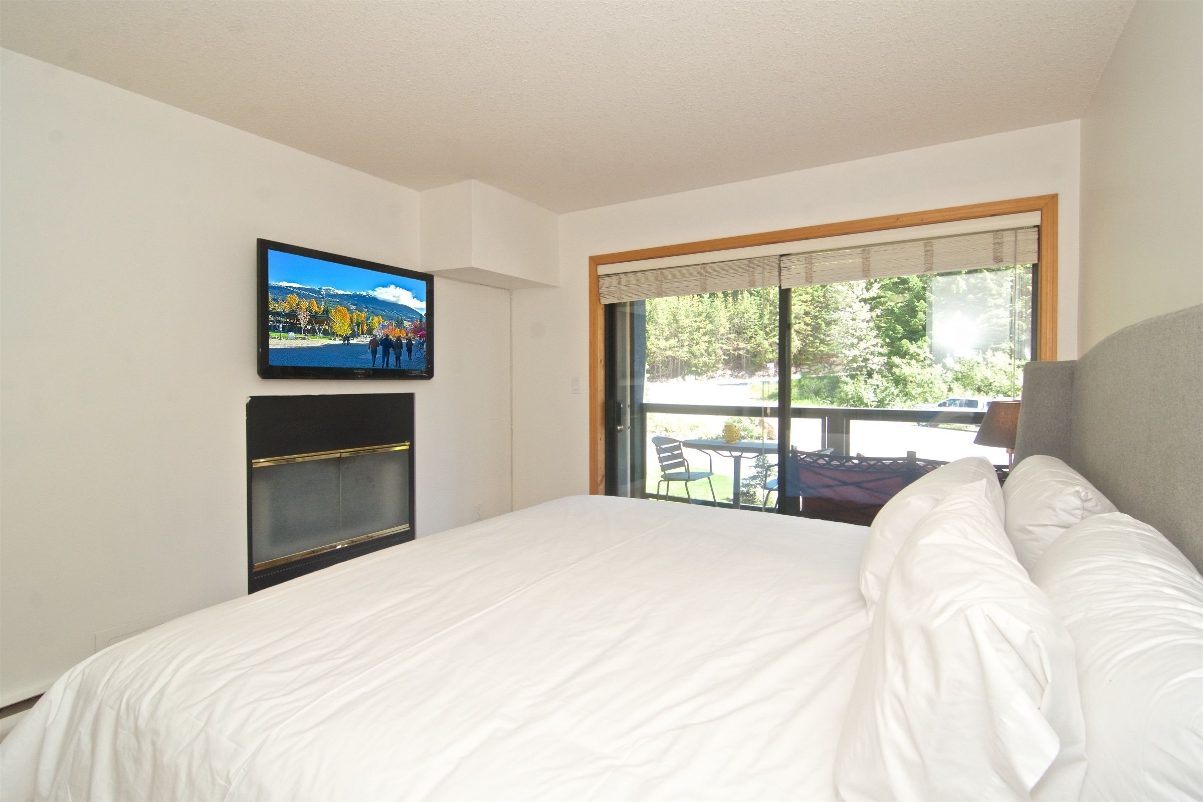 Quarto de hotel com cama, televisão fixada na parede e janela com vista para o exterior.