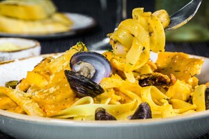 Uma tigela de massa com amêijoas e vegetais.