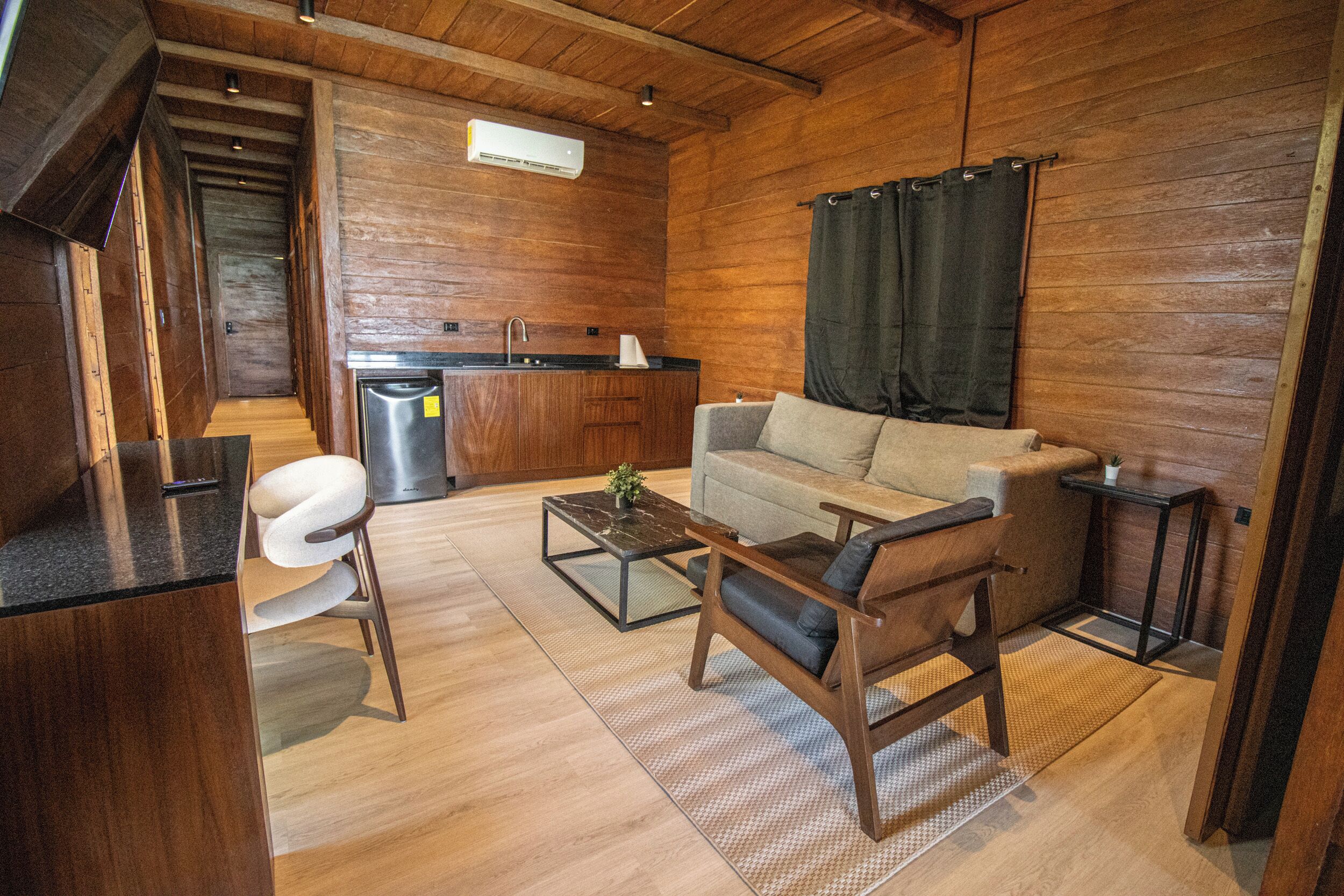 Um espaço compacto com cozinha compacta, um sofá, uma mesa de centro e uma cadeira.